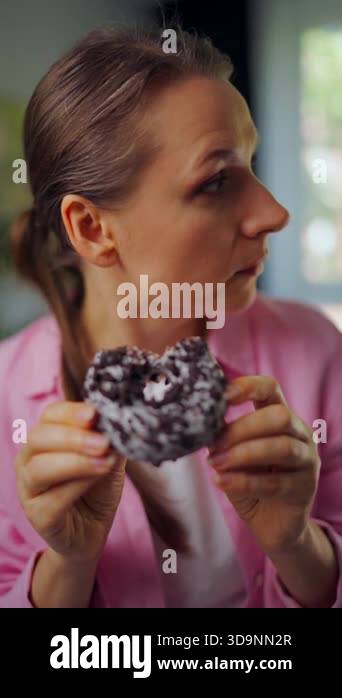 Eating disorder. Woman eating a donut and looking around to make sure ...