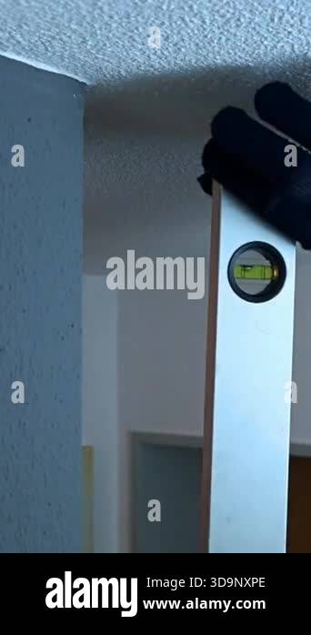 A person uses a level tool to ensure proper alignment of a wall during ...