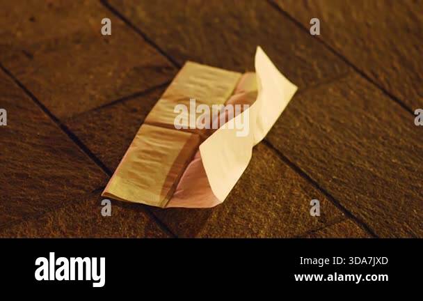 Thin paper strip fluttering and sliding along pavement in wind ...