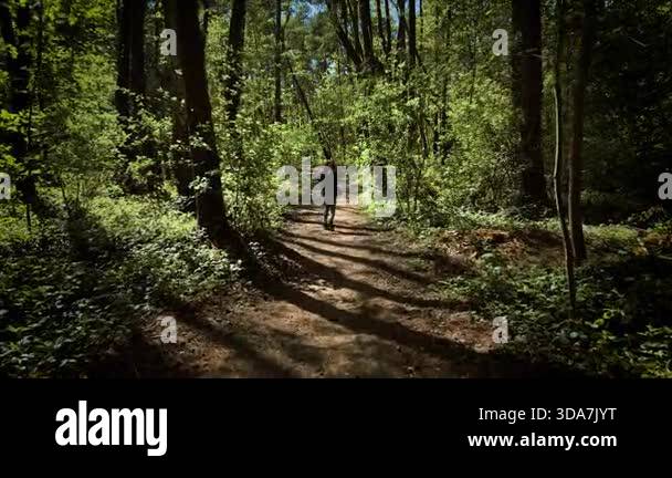 Frightened woman running through forest and looking back in fear ...