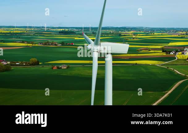 Wind turbine rotating above colorful farmland generating clean ...