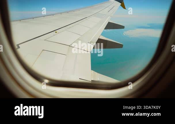Airplane flying above ocean with visible coastline and white cloud bank ...