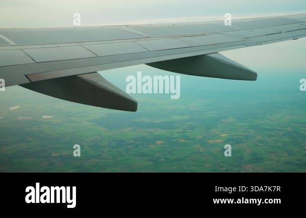 Aircraft flying above green fields in misty weather with visible haze ...