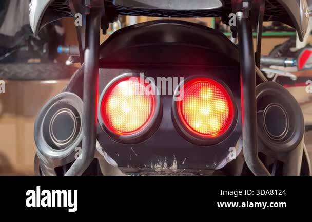 red motorcycle taillights glowing in garage close-up rear view of twin ...