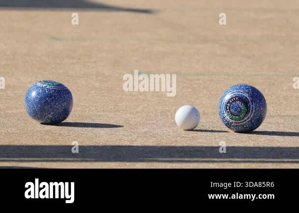 A lawn bowls game unfolds on a sunny day, capturing precise movements ...
