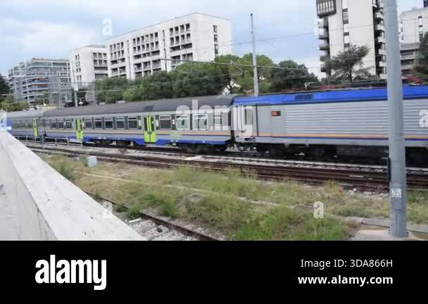 blue and grey passenger train standing on railway tracks in an urban ...