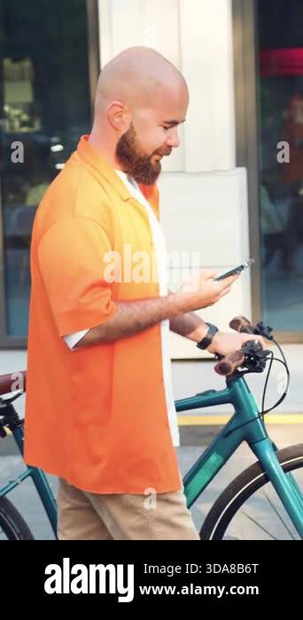 Hipster man using smartphone while walking with bike at urban area ...