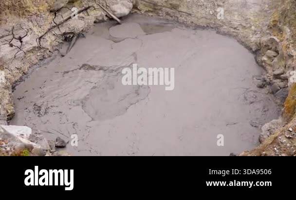Volcanic pit with mud and boiling water with steam rising to the ...