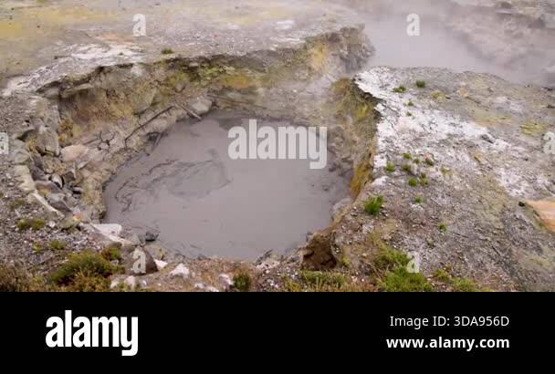 Volcanic pit with mud and boiling water with steam rising to the ...