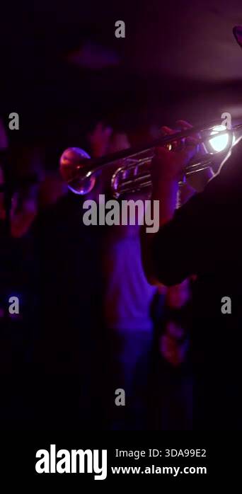 Vertical. Close-up of a shiny trumpet illuminated with a vivid blue ...