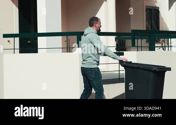 Man pushing trash bin near building entrance Stock Video Footage - Alamy