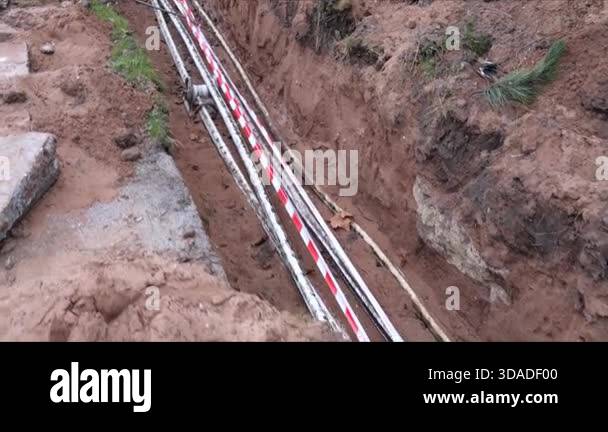 Laying electric cable in a deep trench with exposed underground ...