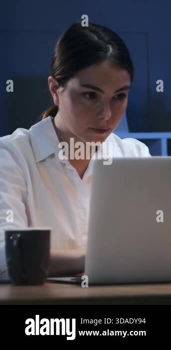 Focused young businesswoman working late at night in dark office ...
