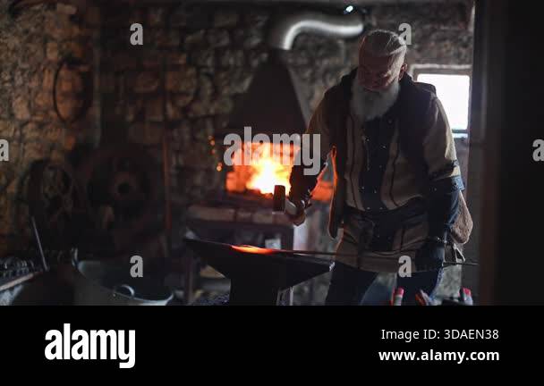 A Viking blacksmith with a white beard and braided hair works intently ...