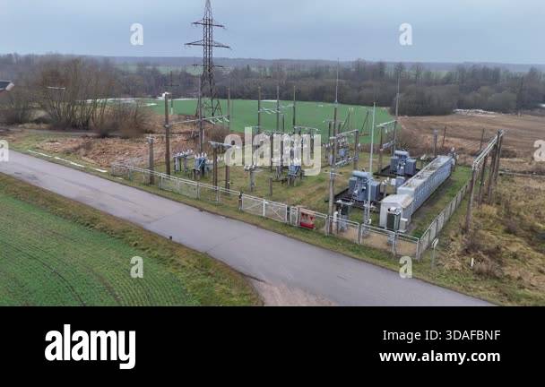 A fenced rural electrical substation surrounded by power lines ...