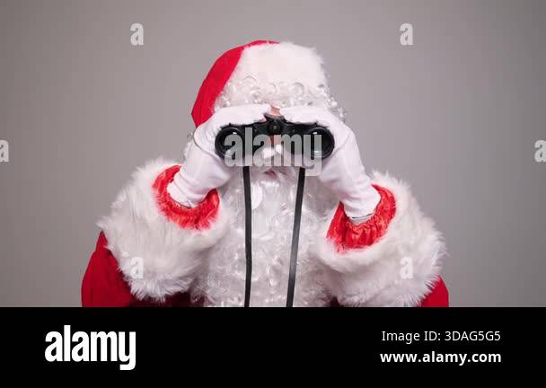 Funny santa claus in a red costume searching for something with ...