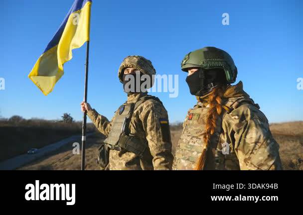 Young soldiers of ukrainian army standing at peak of hill with raised ...