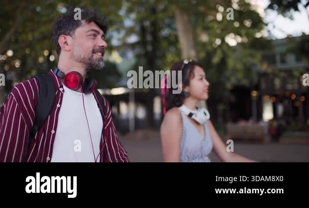 Two friends walking side by side, engaged in conversation, wearing ...