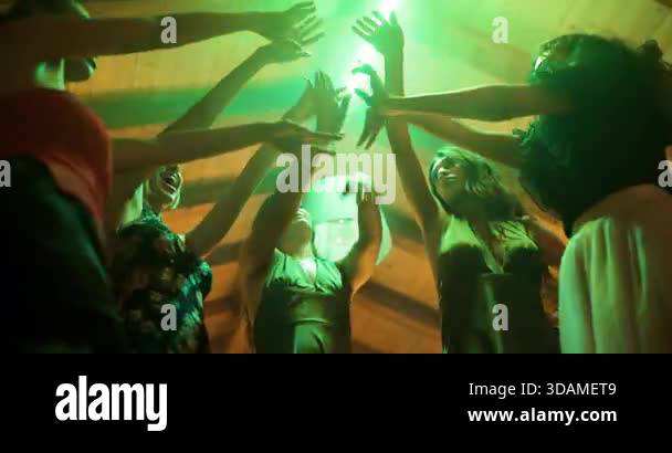 Friends in a circle put their hands up together. They smile and laugh ...