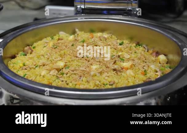 large frying pan. A dish of rice and pieces of vegetables. Steam comes ...