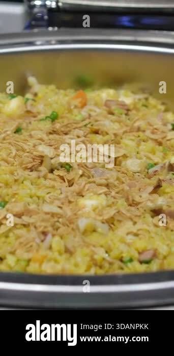 large frying pan. A dish of rice and pieces of vegetables. Steam comes ...
