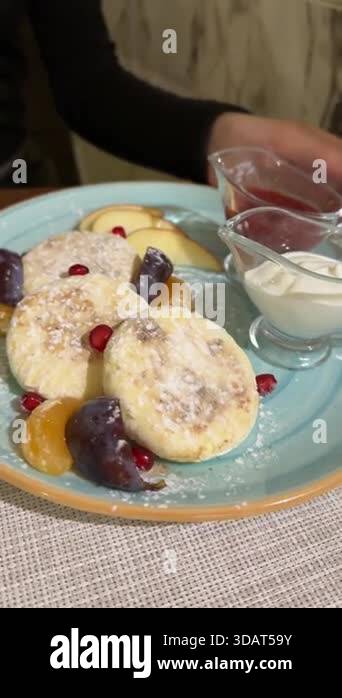Eating cottage cheese pancakes, syrniki with fresh berries, cream and ...