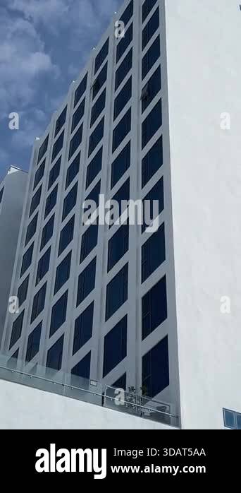 Tilt up shot of high multi-storey white hotel building on the beach ...