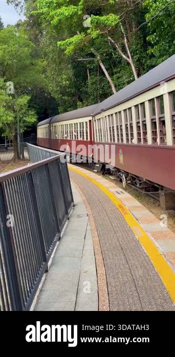 A classic maroon passenger train travels slowly along a curved track ...
