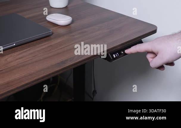 Close-up of a person's hand pressing the up button on an adjustable ...
