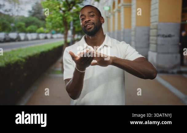 Man smiling and clapping hands on a city street in front of a building ...