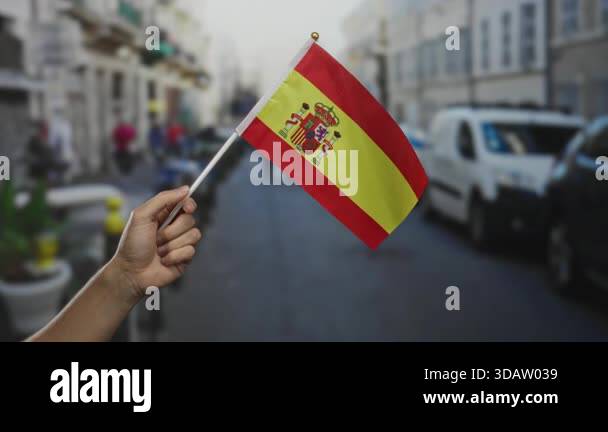 Man hand holding spanish flag in a vibrant city street, symbolizing ...