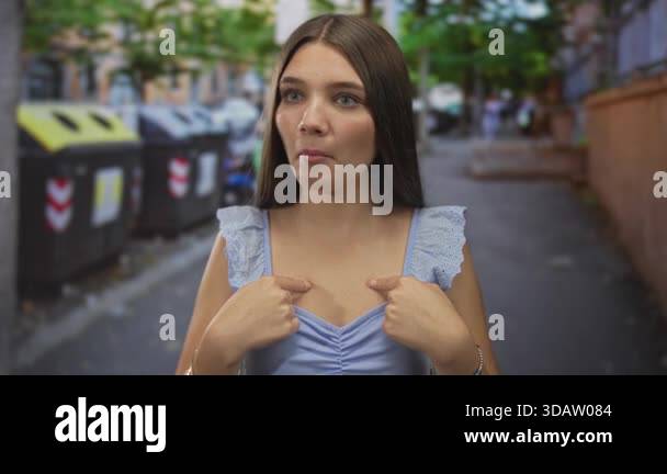 Caucasian teenage girl wearing blue top points fingers to chest by ...