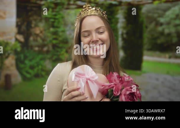 Woman wearing golden crown holding heart shaped gift box and pink ...