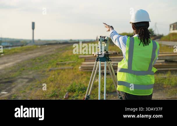 African american land surveyor using a theodolite on a tripod for ...