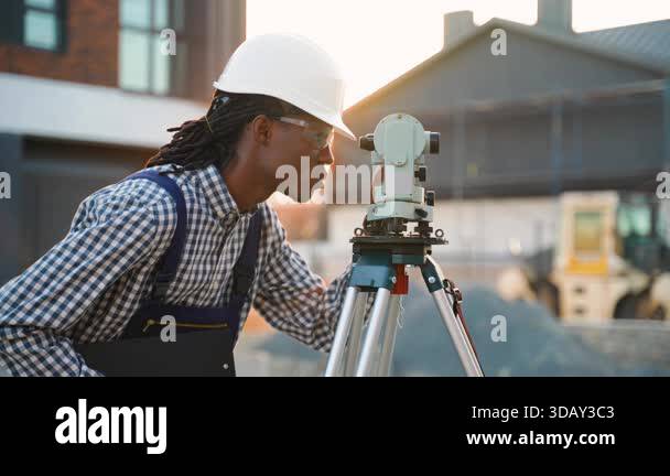African american surveyor using a theodolite for land surveying at a ...