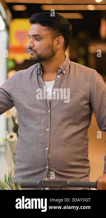 Young indian man pushing a shopping cart through a supermarket aisle ...