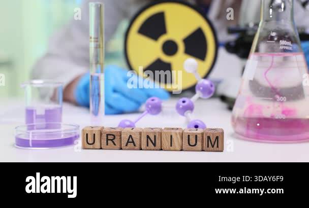 Word Uranium on wooden blocks near purple liquids and molecular ...