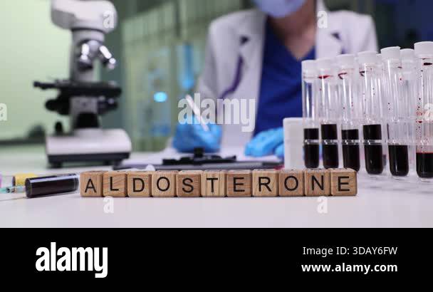 Wooden blocks spell word Aldosterone near blood test tubes. Laboratory ...