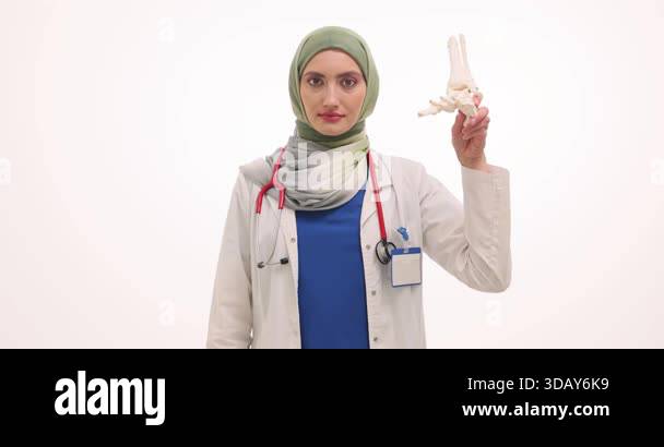 Woman doctor in hijab holds in hands foot skeleton model and pill ...