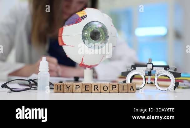 Wooden blocks spell word Hyperopia near giant eyeball model on desk ...