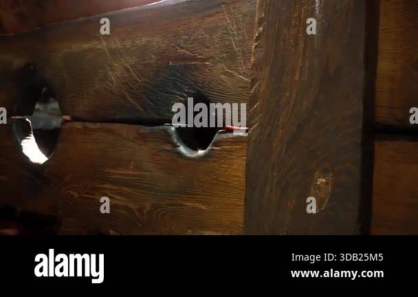 Dark medieval pillory punishment stocks made of old, weathered wood illuminated by a flickering ...