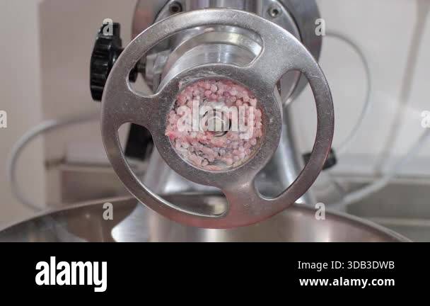 Minced meat slowly comes out of electrical mechanism and falls into ...