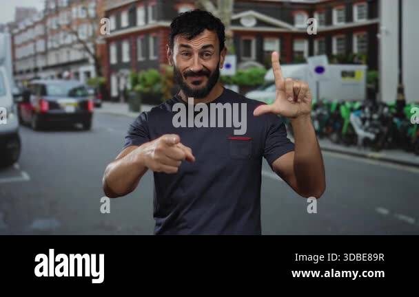 Hispanic man outdoors on a street making loose hand gestures in front ...