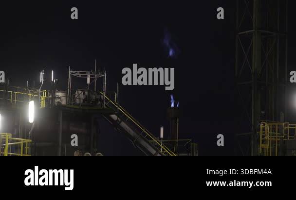 Natural gas torch nozzle at an oil refinery flame in the dark, heat ...