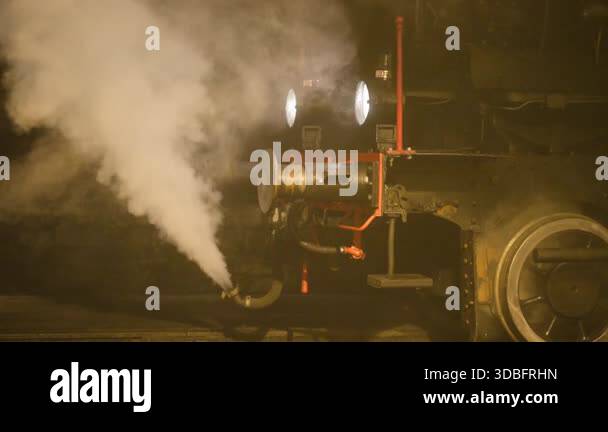 Front of a vintage steam locomotive releasing dense white steam ...