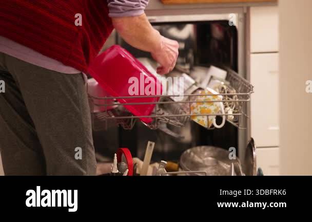 Unrecognizable older woman loading dishwasher in real domestic setting ...