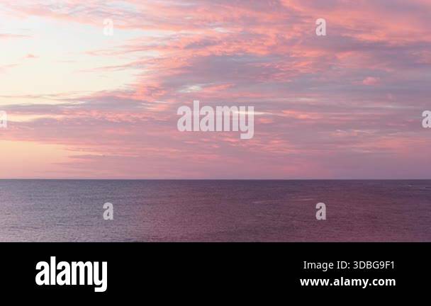 Beautiful calm ocean waves under a dramatic pink and purple sky at dusk ...