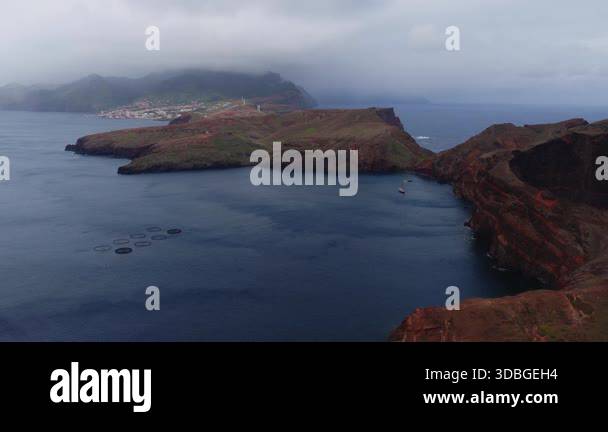 Aerial sweep shows rust red cliffs, walking paths, and a narrow ...