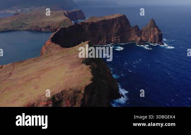 Aerial daylight pan shows Ponta de Sao Lourenco, jagged red cliffs ...
