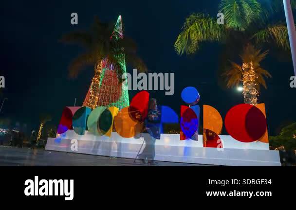 Night in Funchal, Madeira shows a lit conical Christmas tree, palm ...